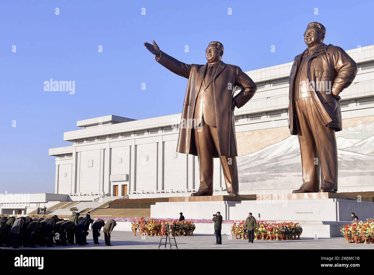 People bow to statues of North Korea's founder, Kim Il Sung (L), and ...