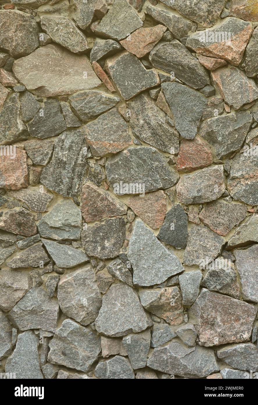 The texture of a strong stone wall of many concreted stones of various ...