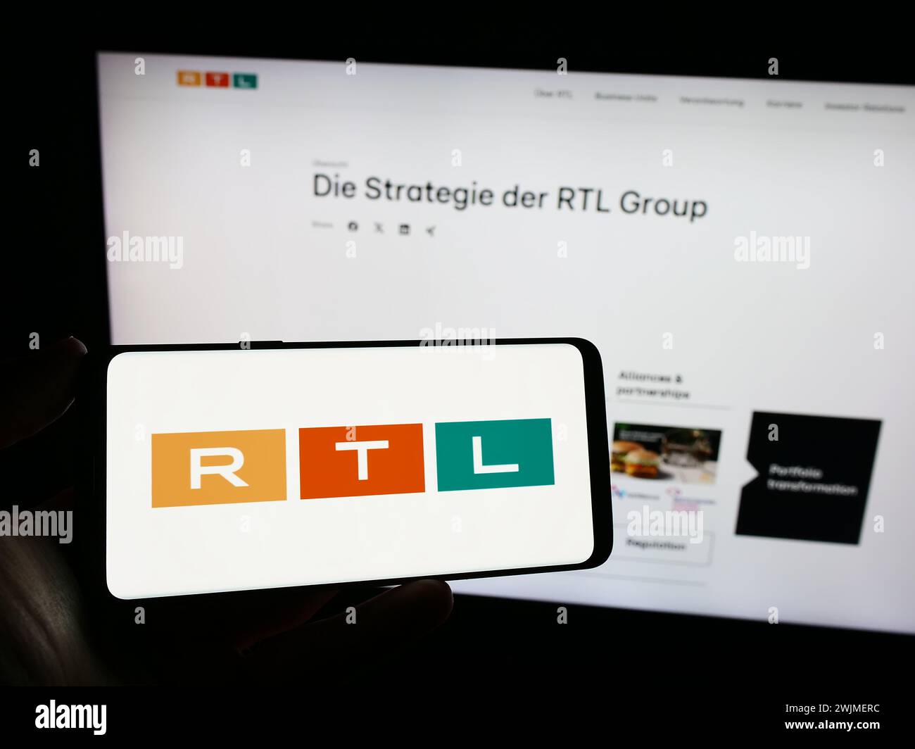 Person holding mobile phone with logo of media and television company ...