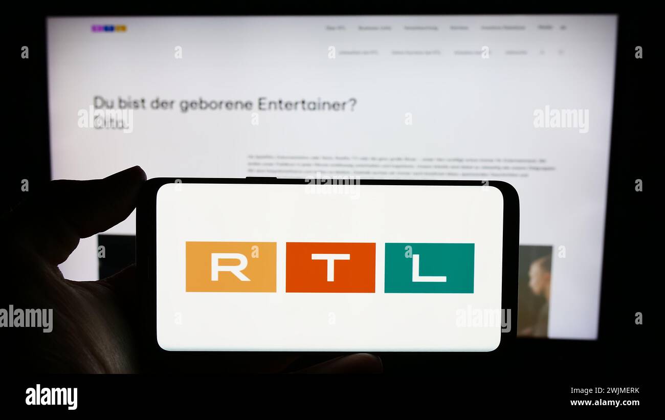 Person holding cellphone with logo of media and television company RTL Group S.A. in front of ...