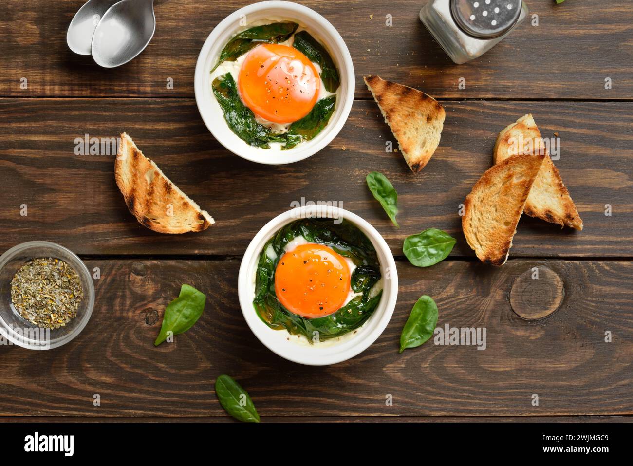 Eggs en cocotte (baked eggs) with cream, сheese and spinach in portion ...