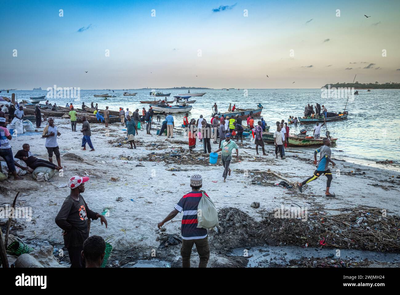 Porters rush around as traditional wooden dhow boats crowded with ...