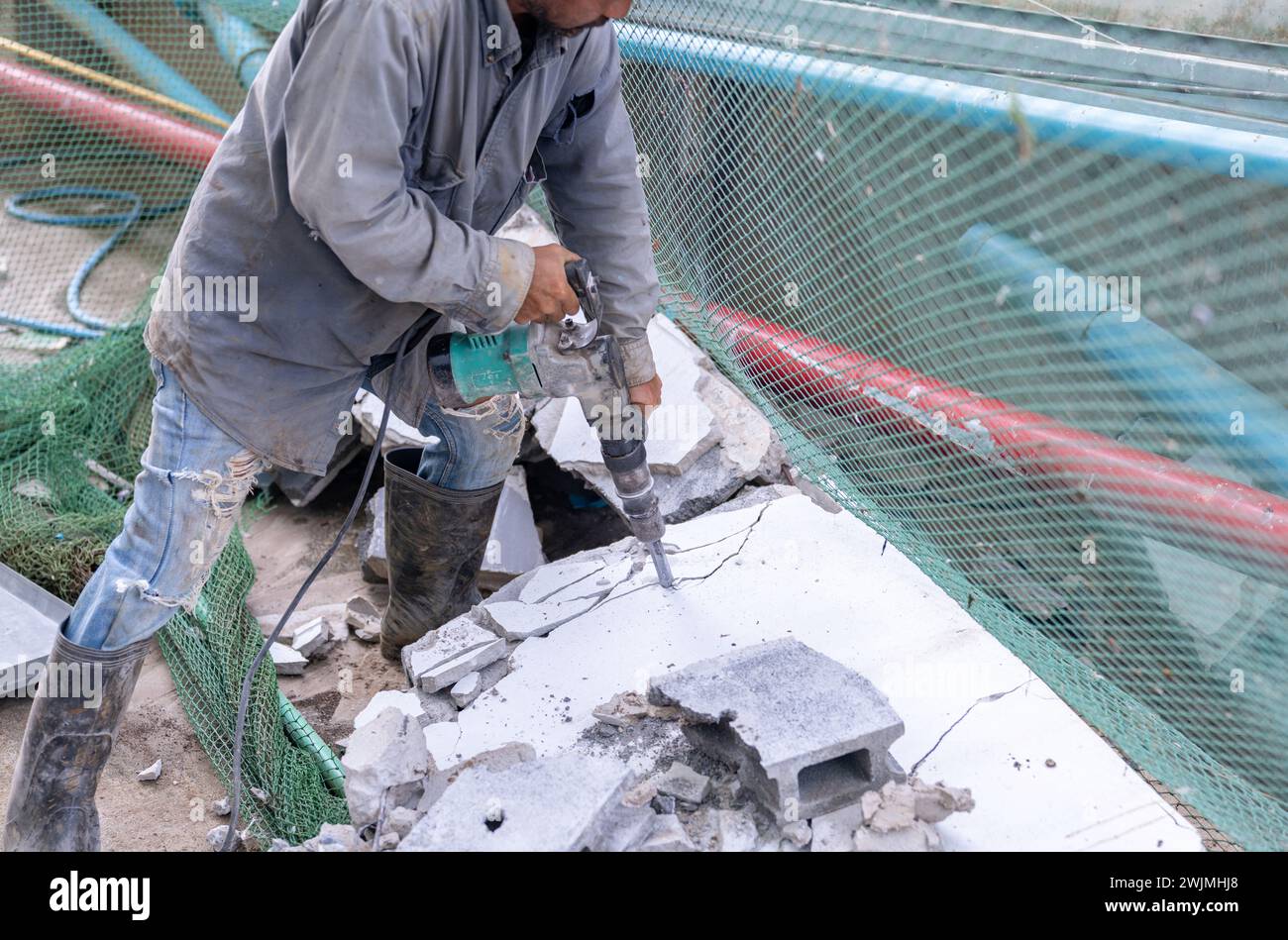 Worker breaking concrete using jackhammer in construction site Stock ...