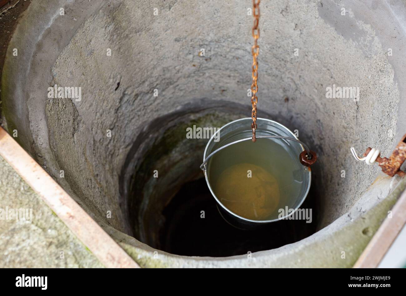 Metal bucket at draw-well in European village. Retro stone water well ...