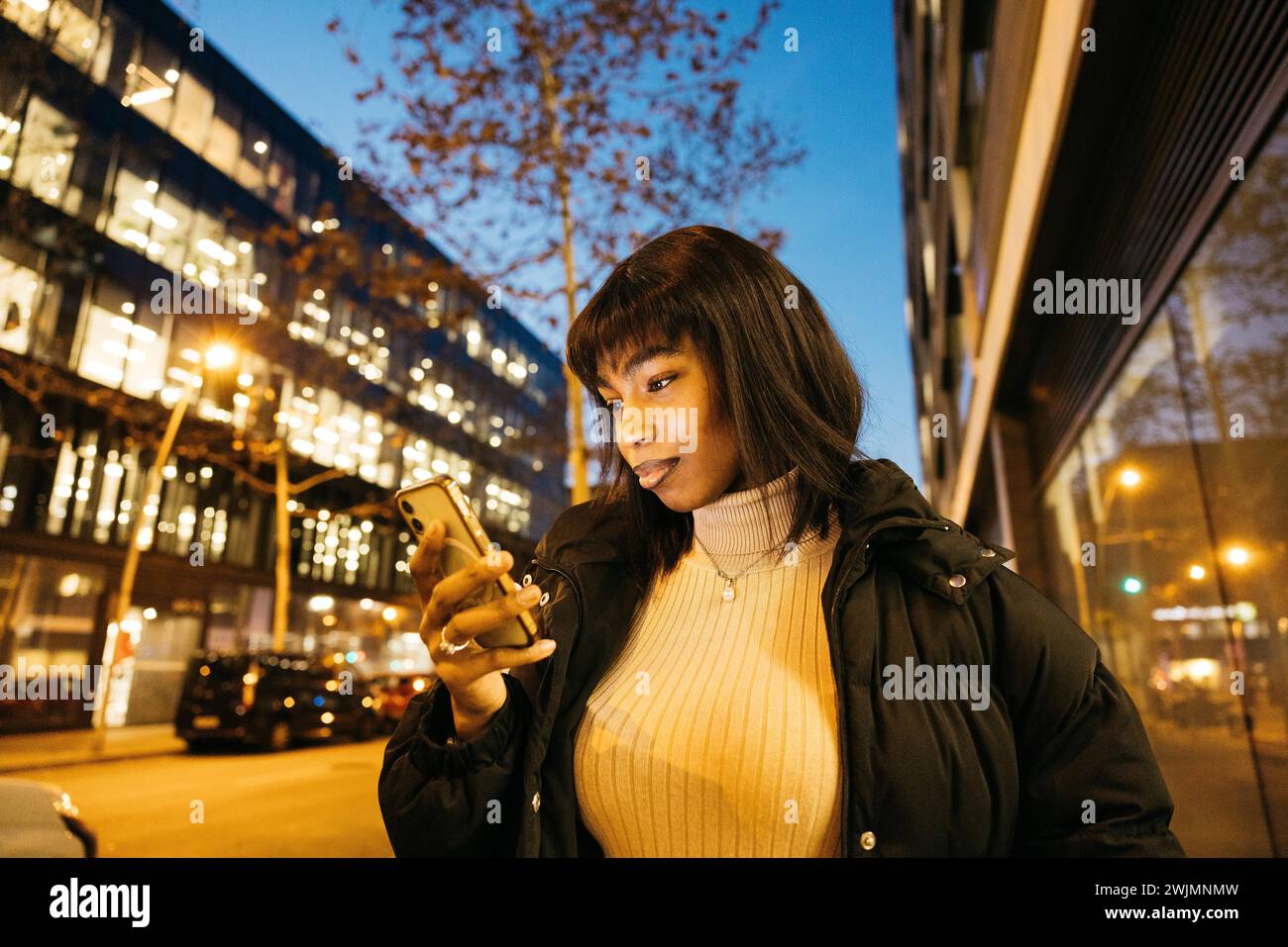 Young beautiful black woman typing an online message on her phone while ...