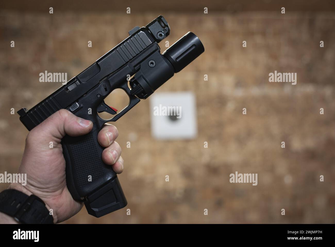 Tactical pistol with a flashlight in a man's hand at a shooting range ...