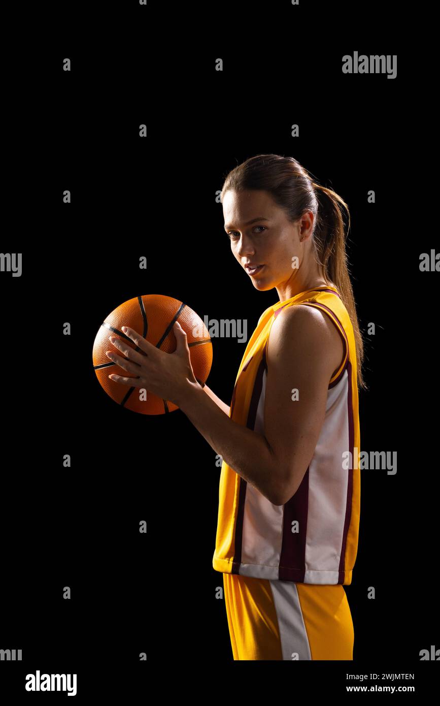 Confident female basketball player ready for game, poses in dark ...