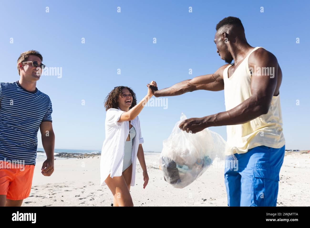 Diverse friends clean up a beach together, collecting trash Stock Photo ...