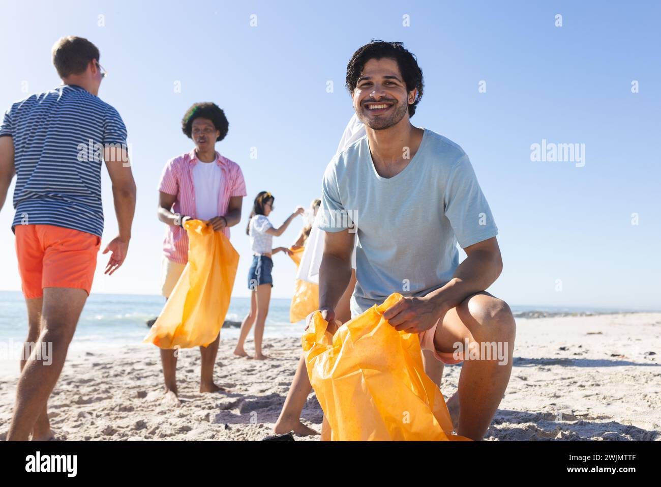 Diverse group of friends cleaning the beach and collecting trash Stock ...