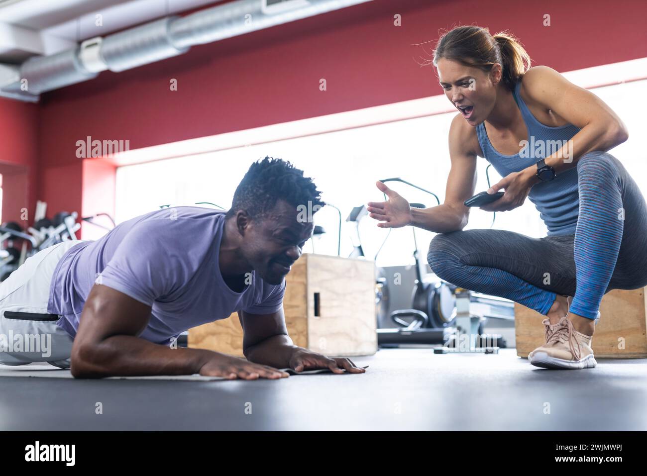 Fit young Caucasian woman coaches a fit African American man at the gym ...