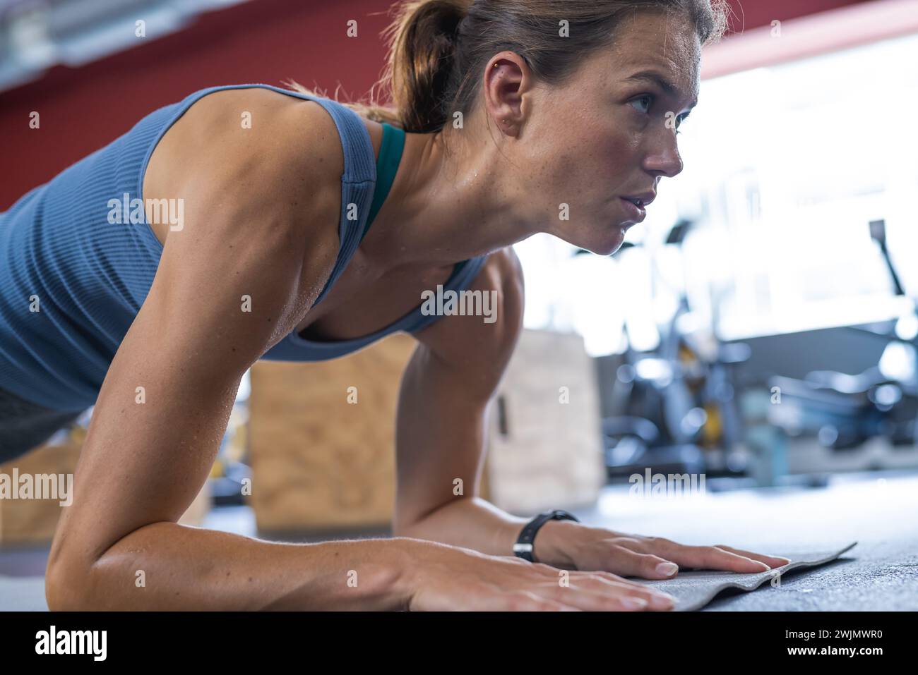 Fit young Caucasian woman performs a plank exercise at the gym. Her ...