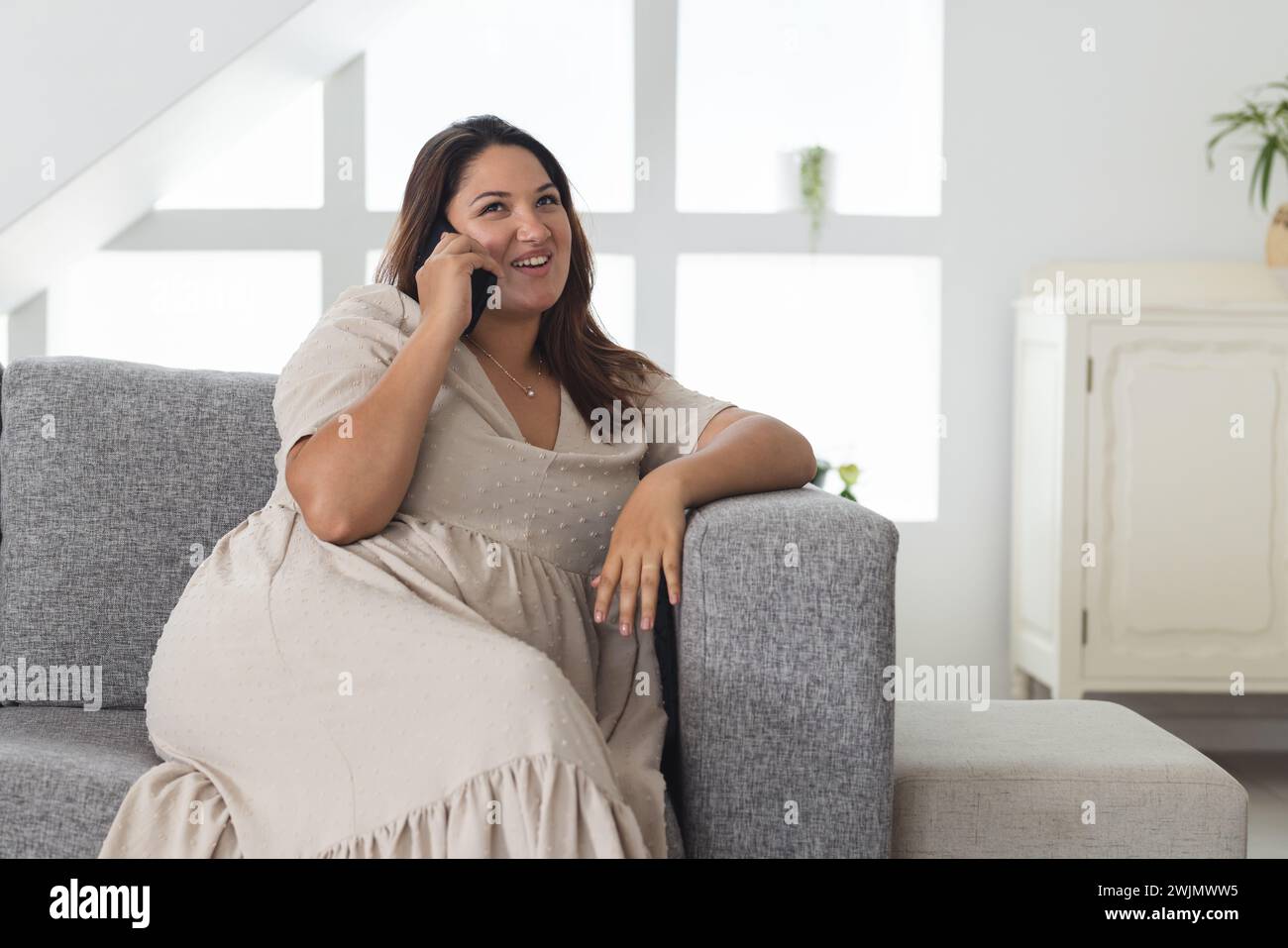 Young plus size biracial woman chats on the phone while relaxing on a ...
