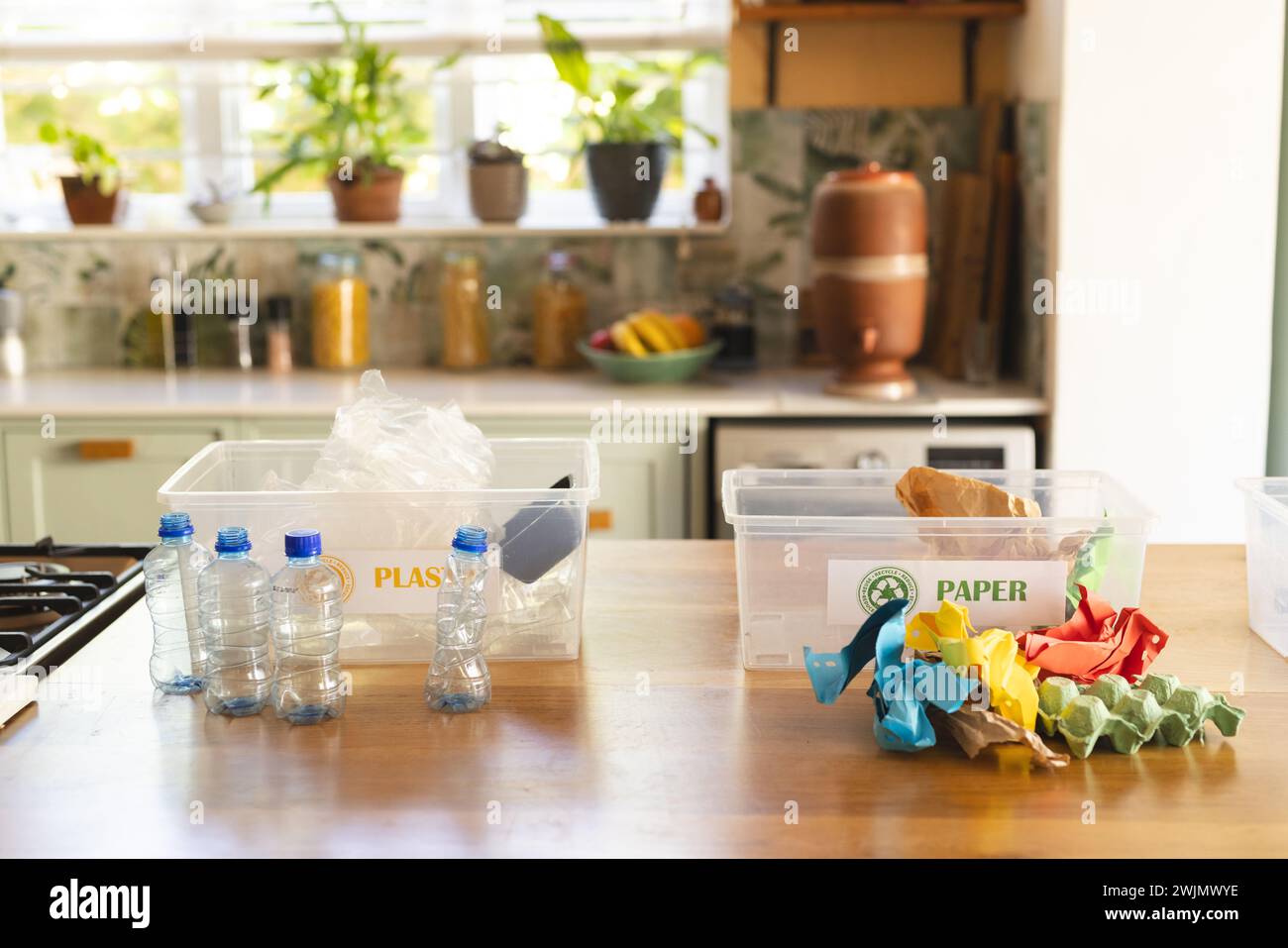 Recycling bins are neatly organized on a kitchen counter. The clear ...
