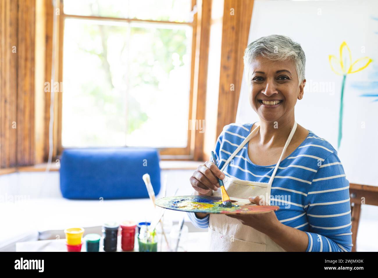 A mature biracial woman paints in a bright home studio Stock Photo - Alamy