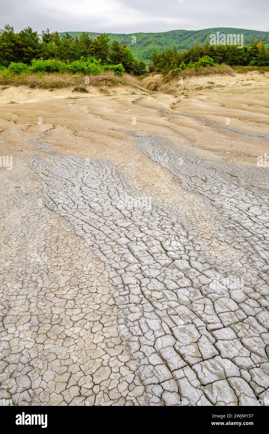 The cracked, arid terrain with dry grass in the backdrop Stock Photo ...