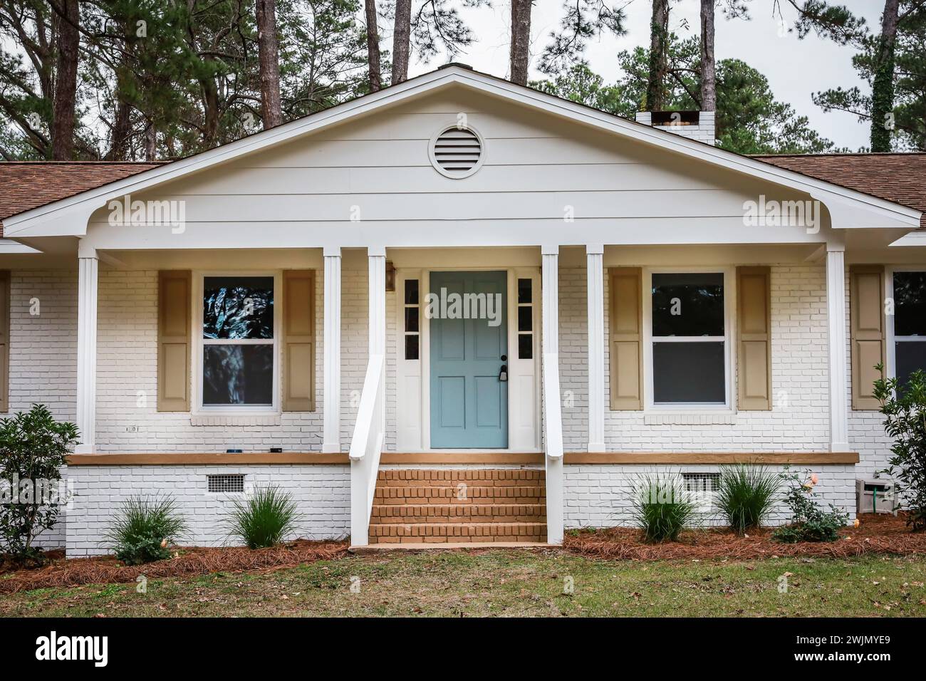 The front exterior entrance of a newly painted white siding brick ranch ...