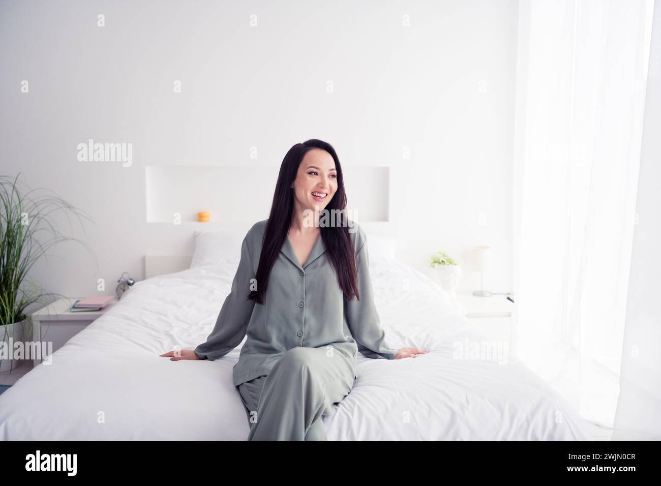 Photo portrait of attractive young woman sit cozy soft bed look window ...
