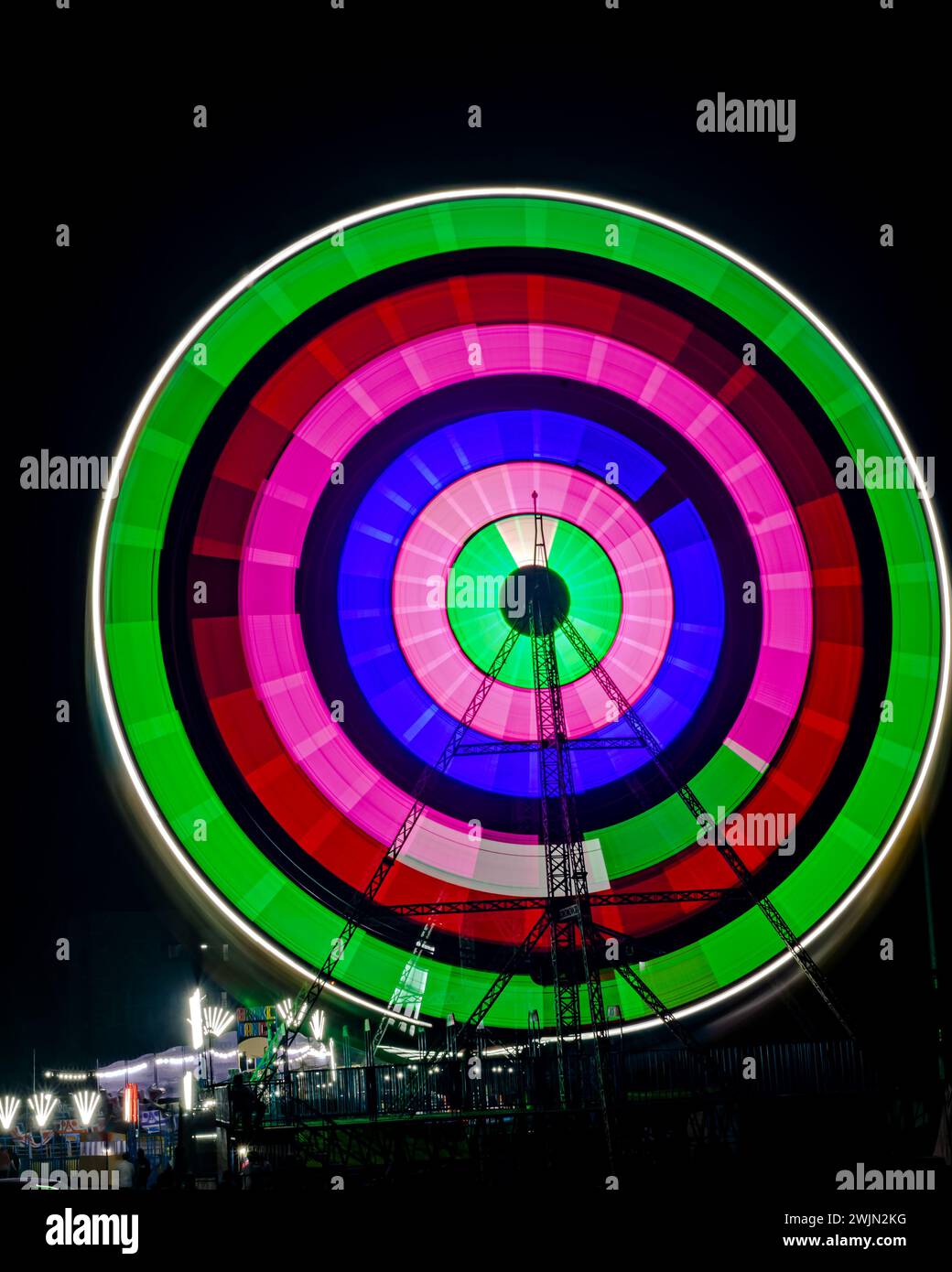 Intentional camera movement, slow shutter blur image of giant Ferris wheel illuminated and ...