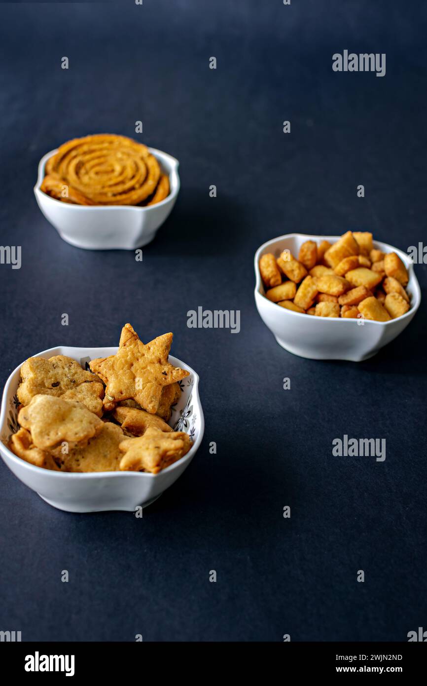 Assorted , fresh Diwali snacks or faral items filled in white bowls ...
