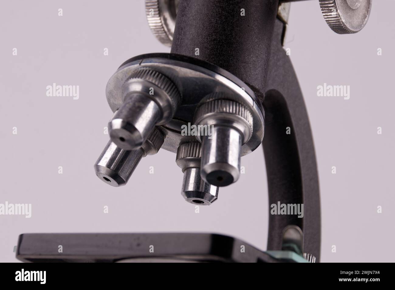 an old microscope stands on a white surface with real shadows, close up ...