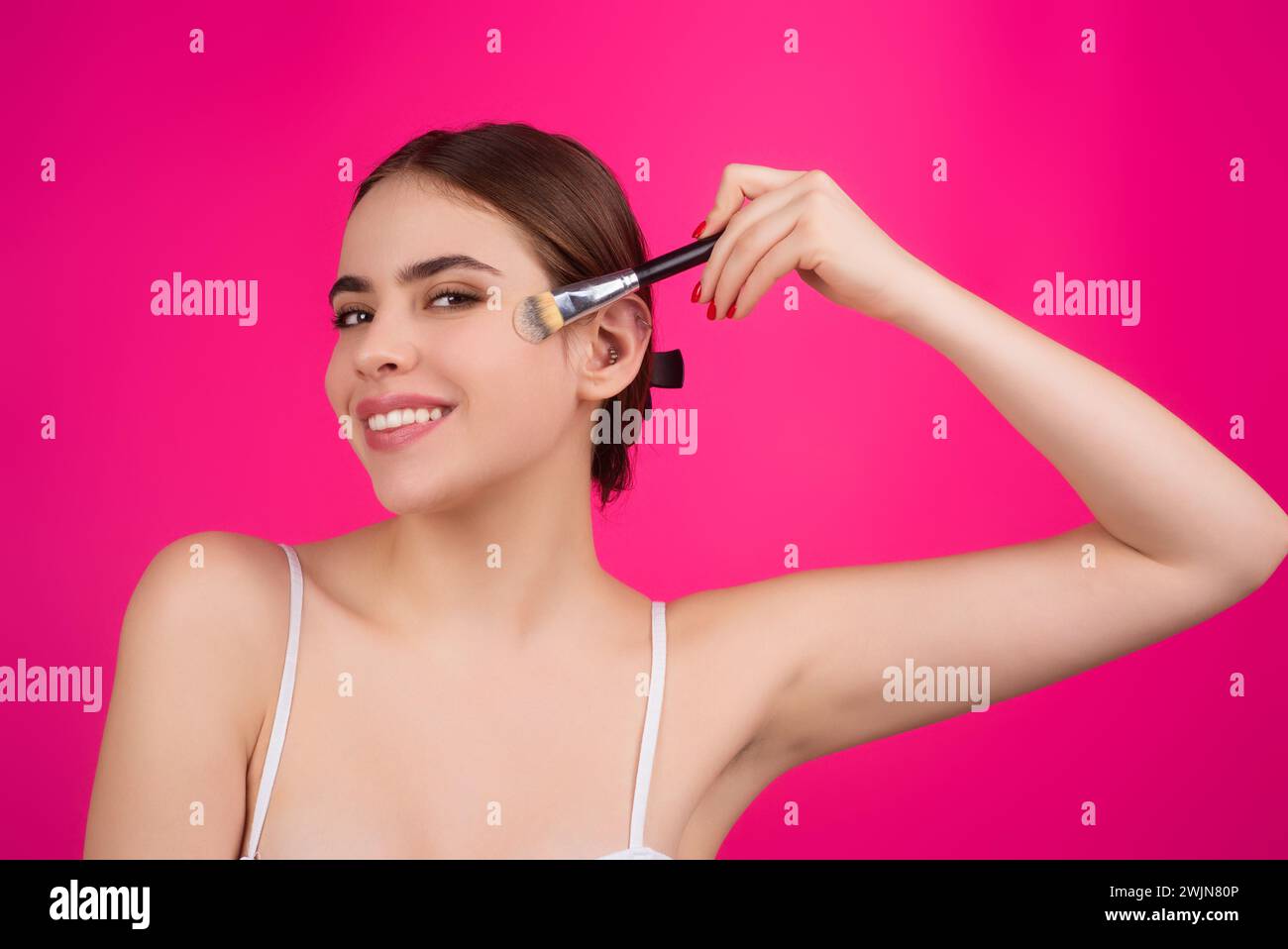 Woman applies powder on the face using makeup brush. Girl doing ...