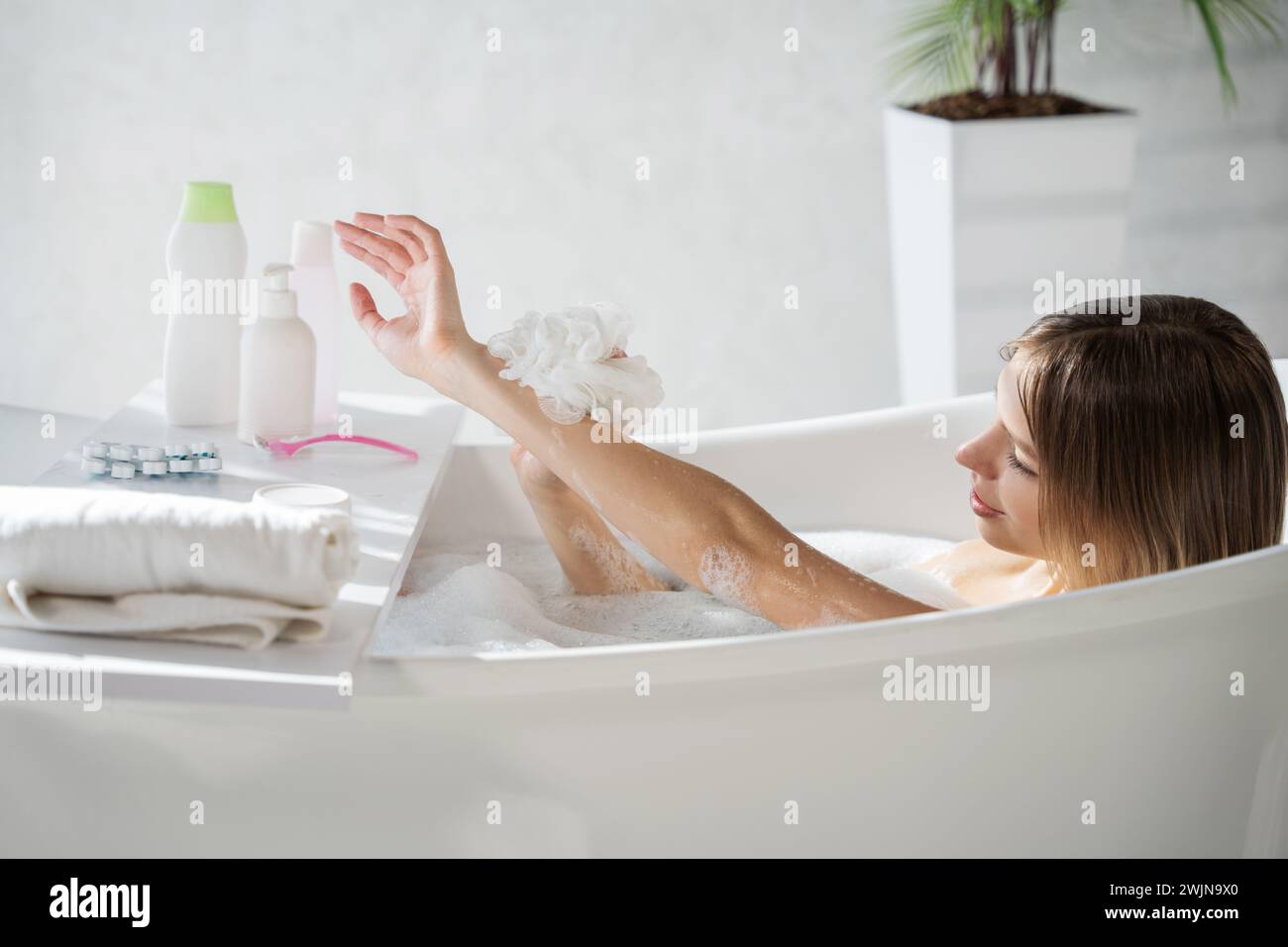 Happy lady washing with soapy sponge in bath Stock Photo - Alamy