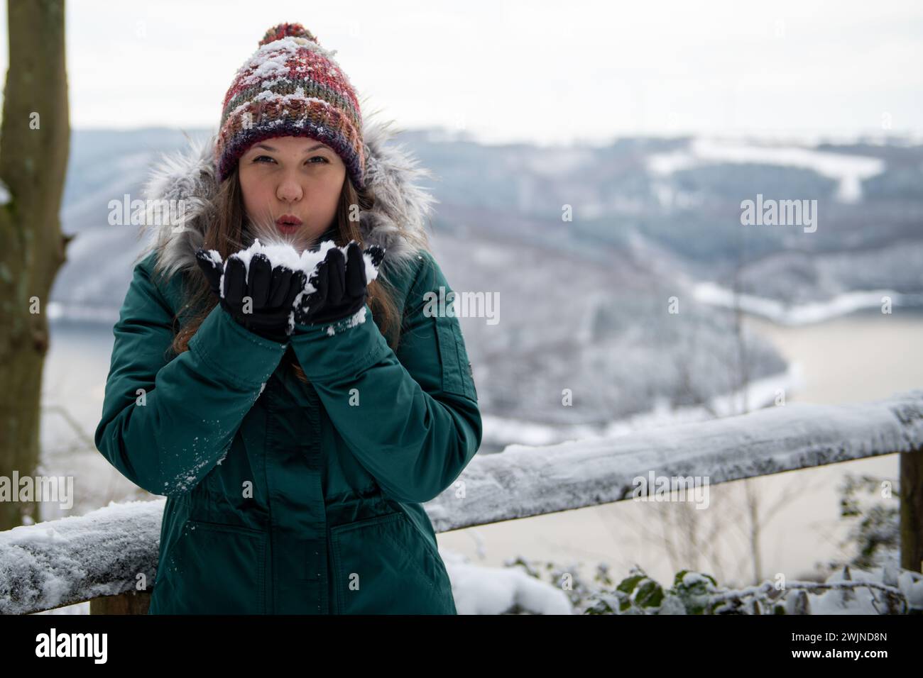 a woman dressed in winter attire, including a teal jacket and a snow ...