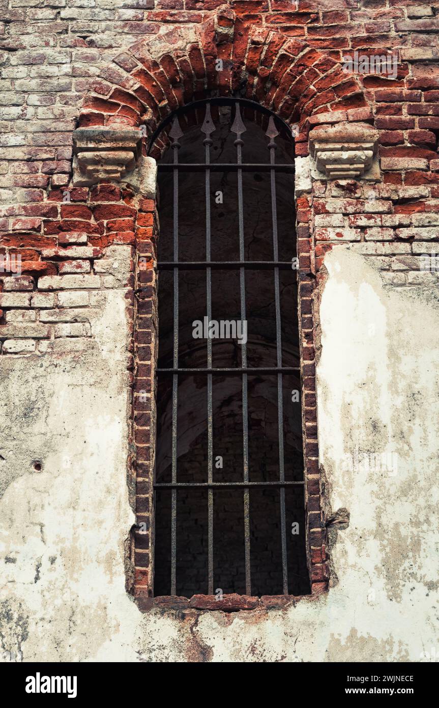 Fragment of a brick wall with a window with a lattice of a medieval ...