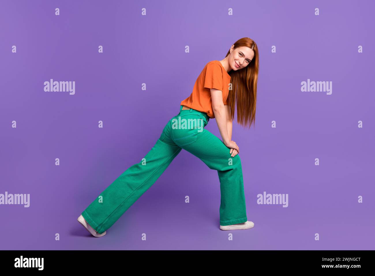 Full body photo of young lady in green jeans posing stretching right ...