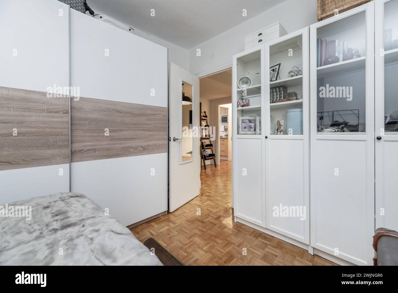 Bedroom with a large bed, white wardrobes with a display case and a ...