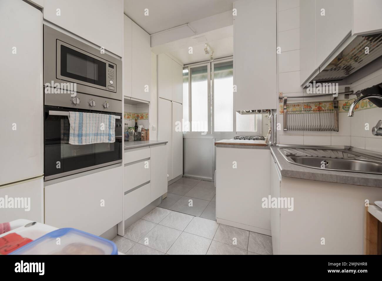 Image of a small kitchen with all the walls covered in white furniture ...