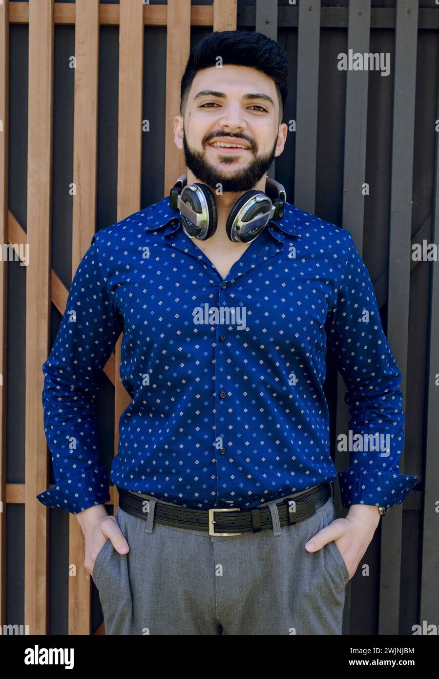 Asian male standing with earphones on neck, hands in pockets Stock ...