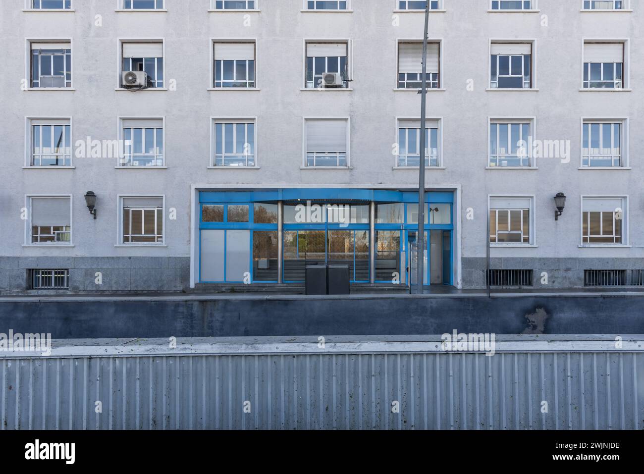 Facade of a building with many square windows and a large metal portal ...