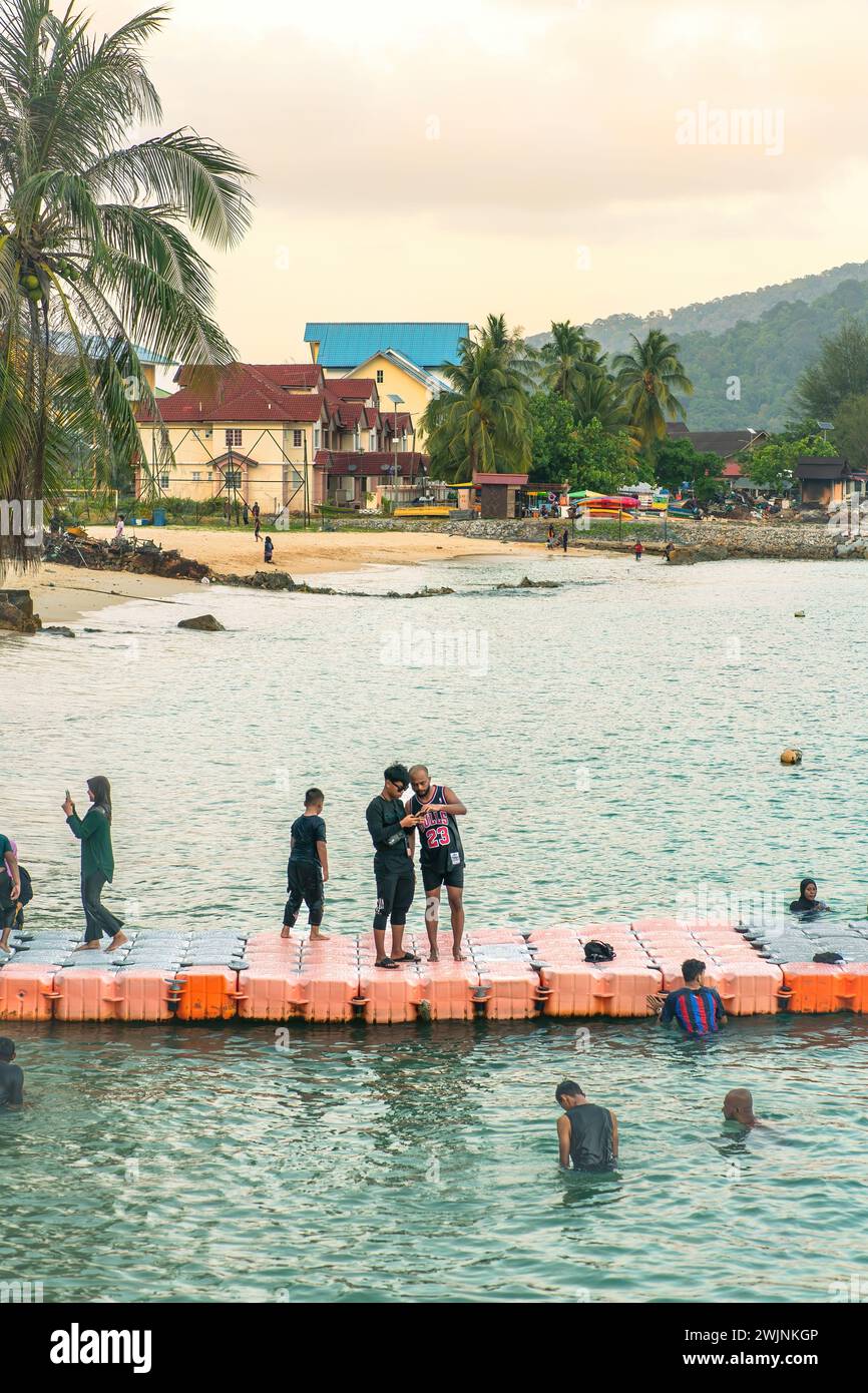 A group of people are having fun at the floating bridge on Perhentian ...