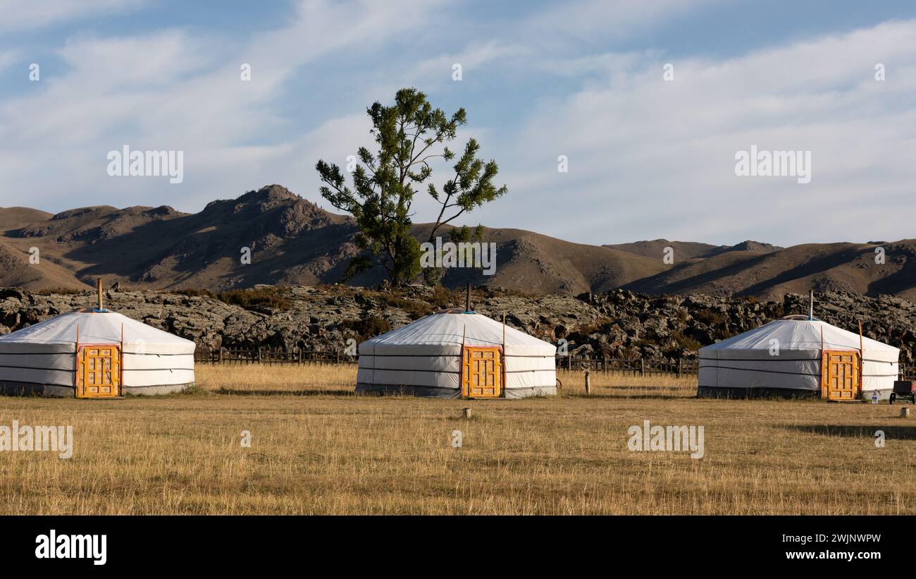 Three yurts stand in the steppe of central Mongolia in front of a huge ...