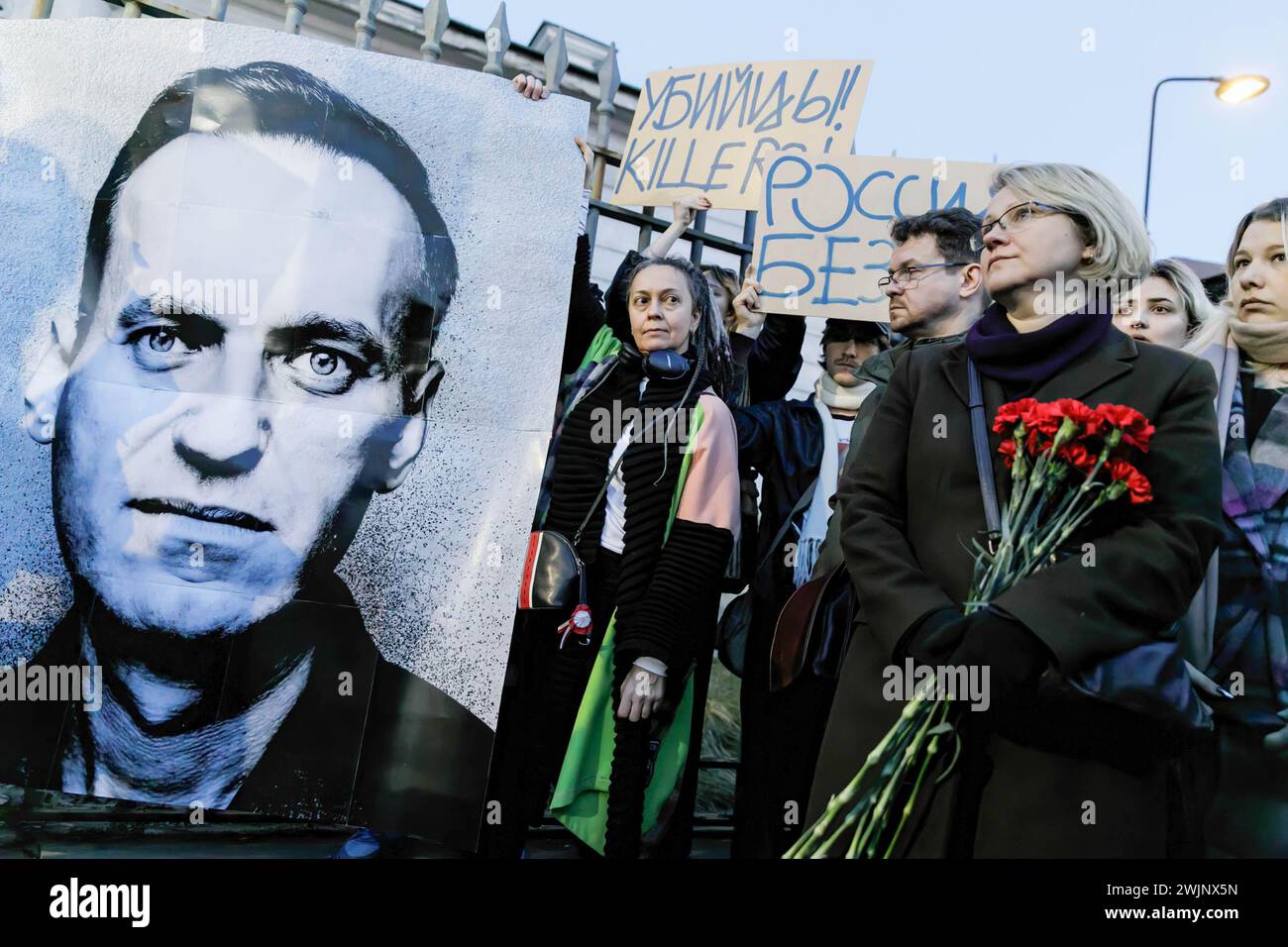 Protesters stand near the portrait of Alexei Navalny in front of the ...