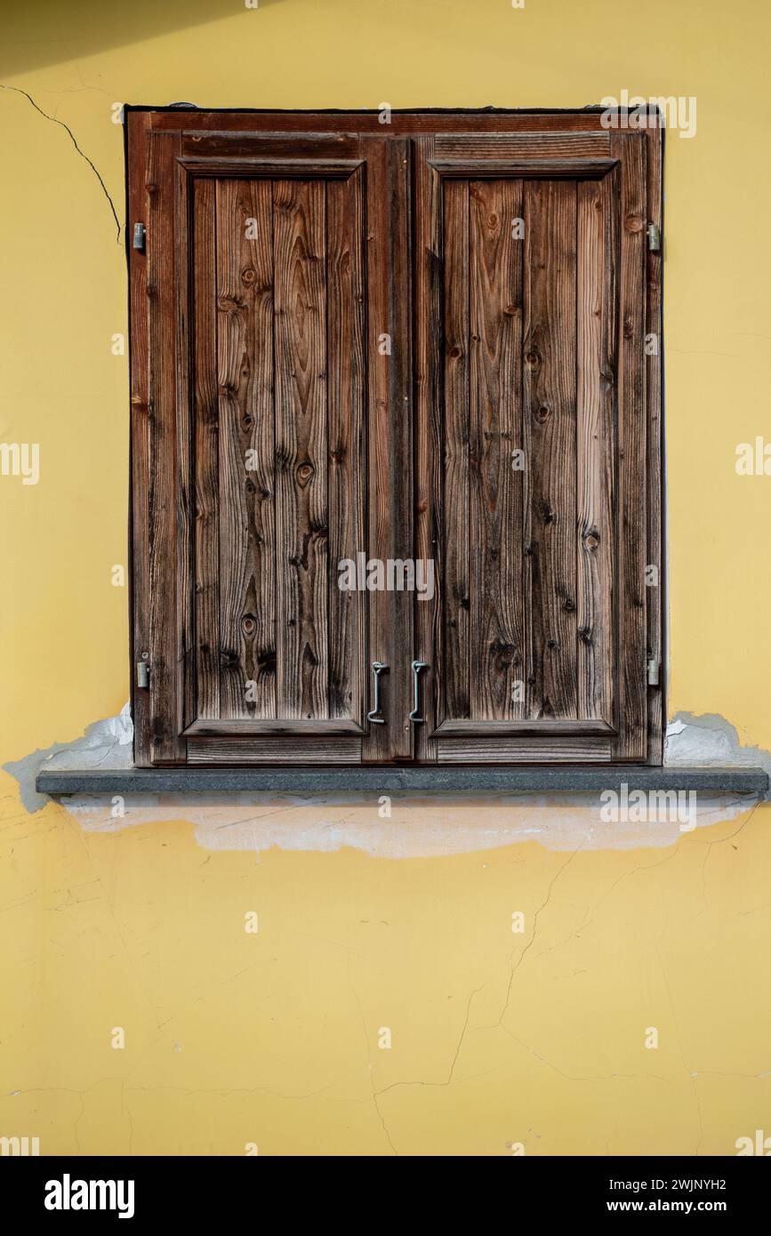 Yellow painted house wall with cracked surface, two windows. Window ...