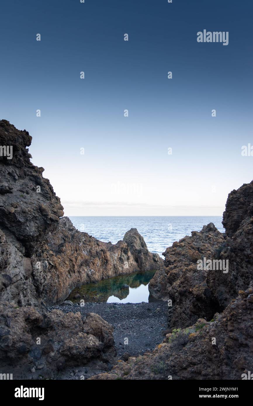 Vertical photo of a natural pool of seawater between volcanic rocks in ...