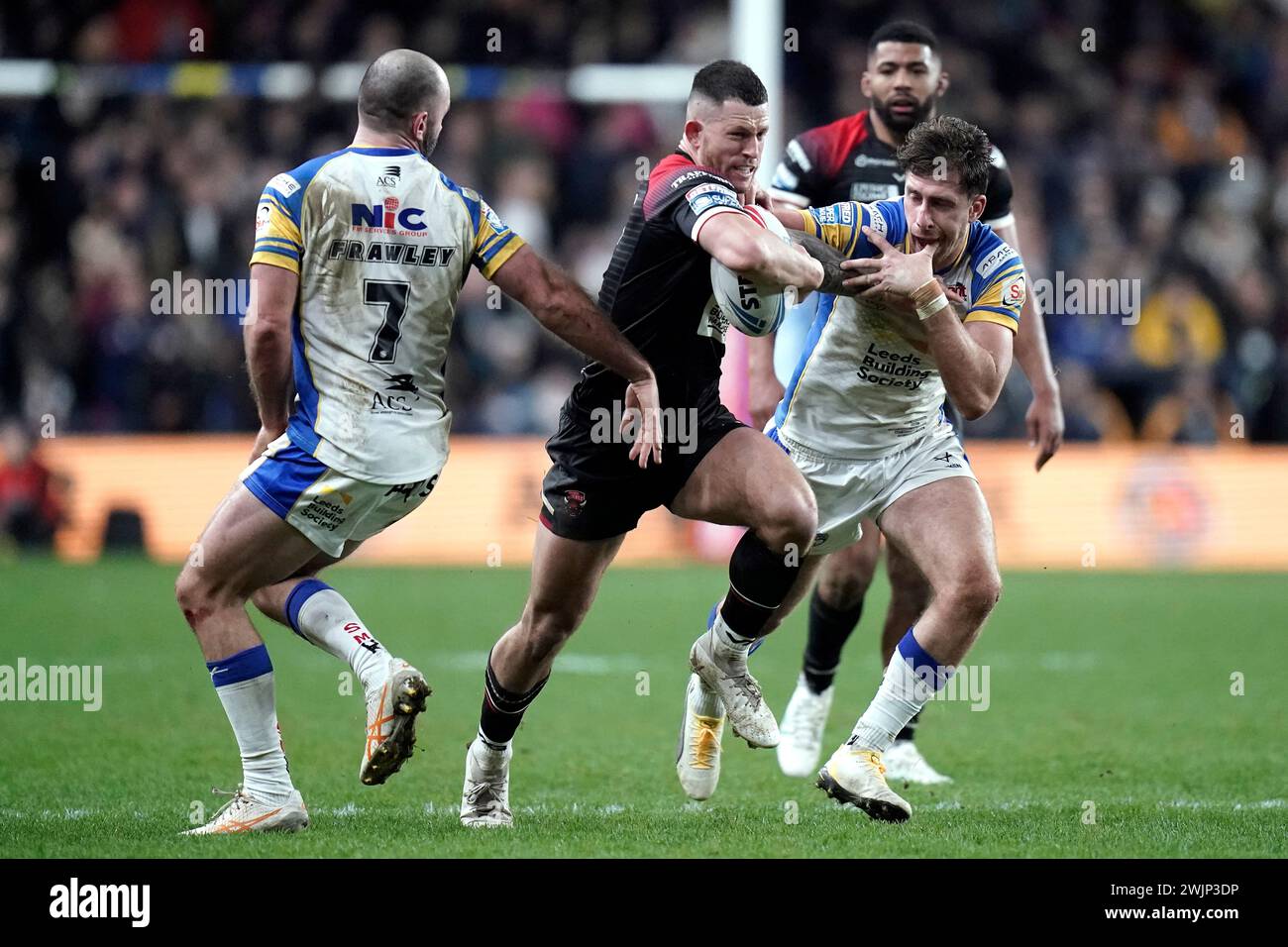 Salford Red Devils' Cade Cust (centre) breaks through the Leeds Rhinos ...