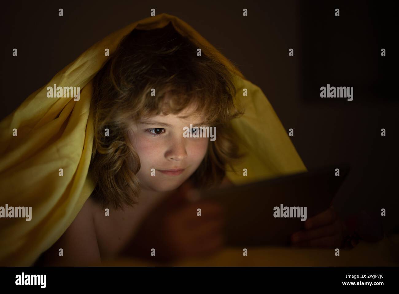 Kid watching tablet before sleeping. Child reads the e-book. Little boy ...