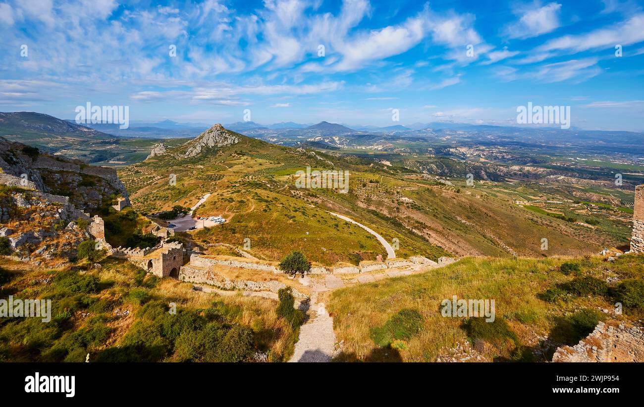 Wide view of a hilly landscape with path and ruins under a blue sky ...