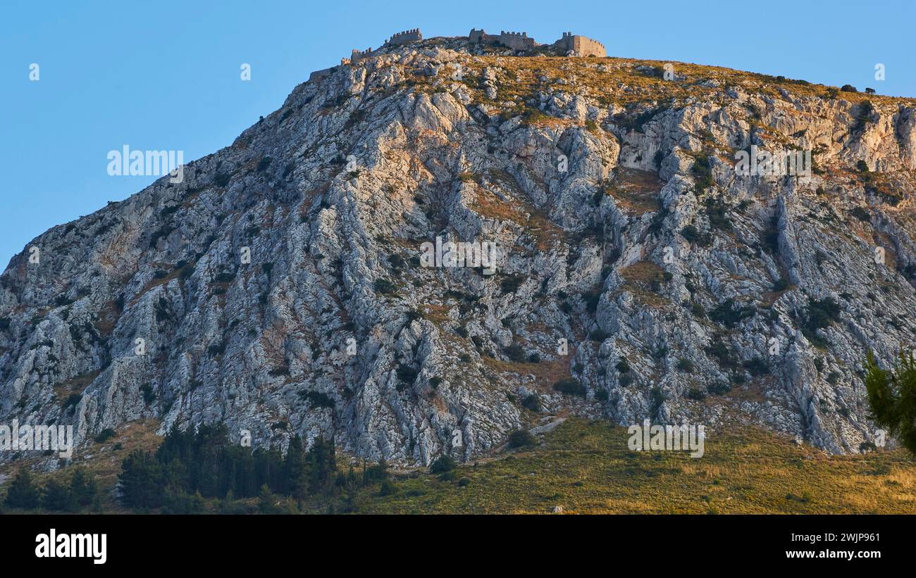 The golden hour illuminates a mountain with an ancient castle at the ...