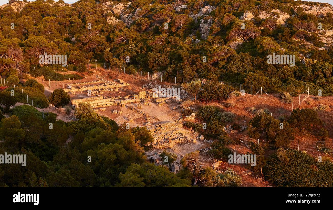 The warm rays of the sun illuminate an ancient ruins site in a hilly ...