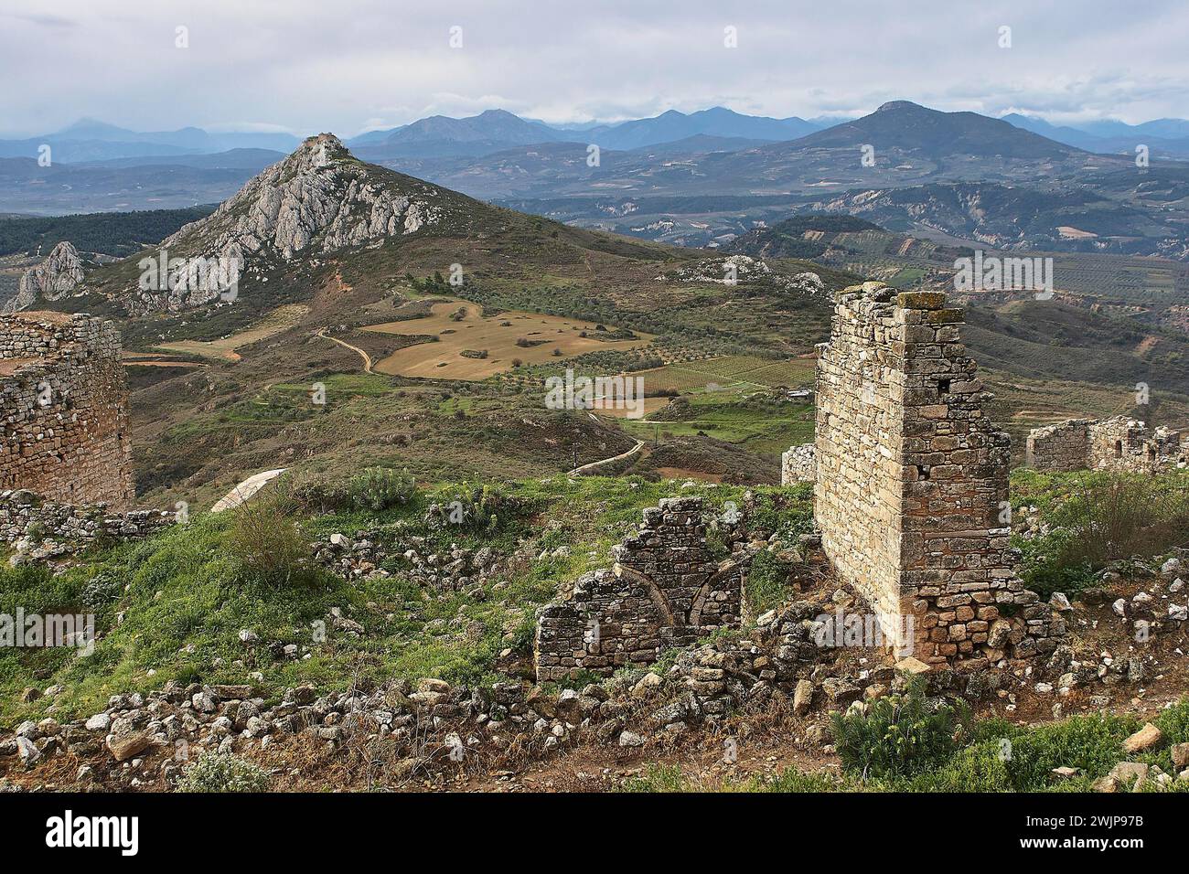 Ruins in front of a mountain range and cloudy sky with green hills in ...