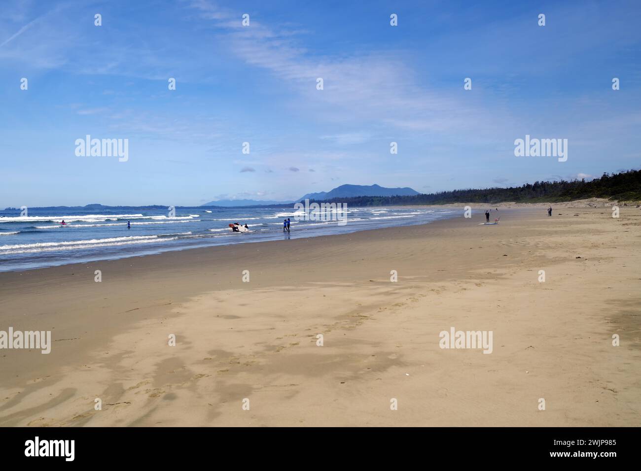 Endless empty sandy beach with swell and mountains in the background ...