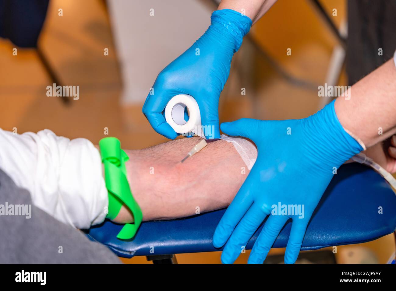 Close-up of a nurse fixing a needle with stripe into the arm of a blood ...