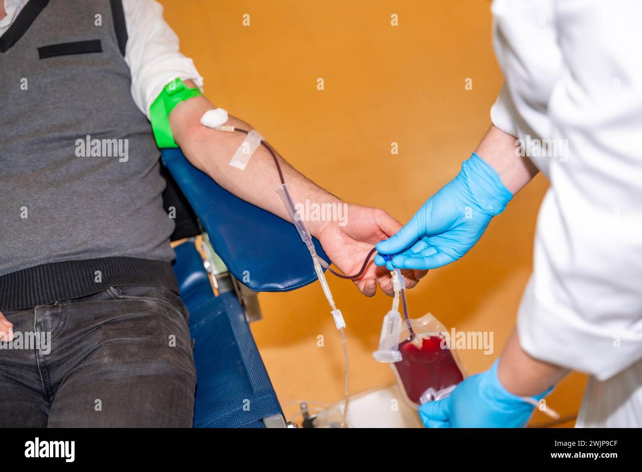 Close-up of a nurse with blue latex gloves extracting blood from a man ...