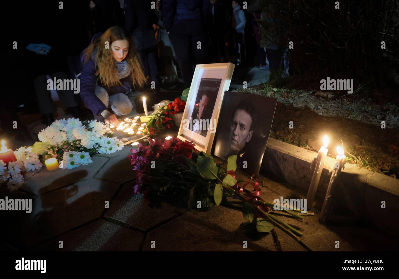 A woman lights a candle as portraits of Alexei Navalny, candles and ...