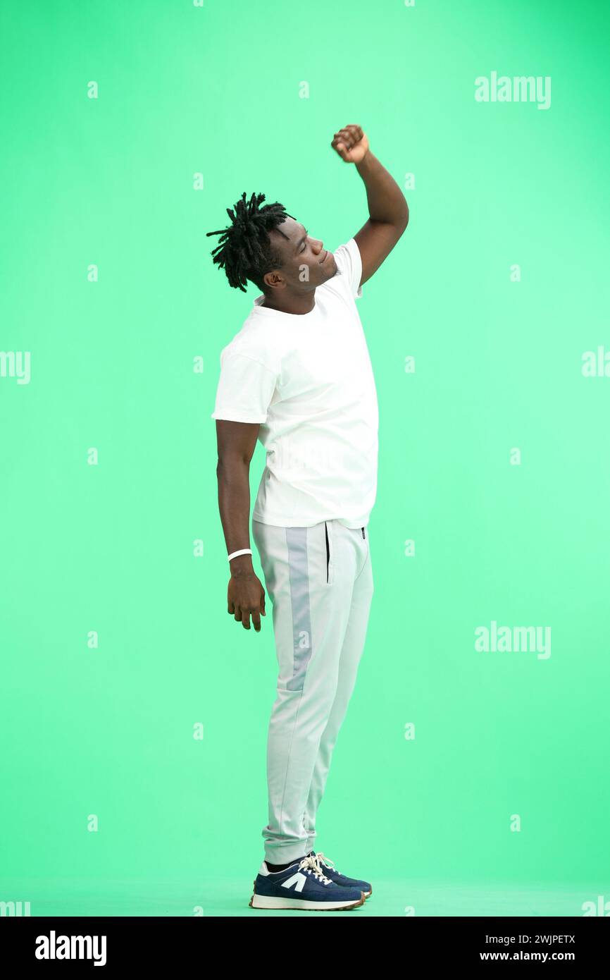 A man, full-length, on a green background, raised his hand up Stock ...
