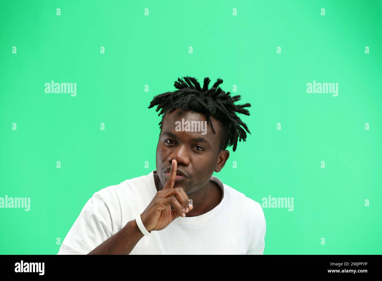 A man, close-up, on a green background, shows a sign of silence Stock ...